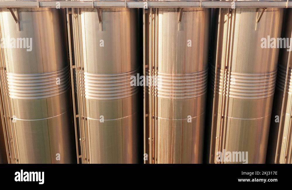 Tall stainless steel tanks connected with pipes: silos in a chemical ...