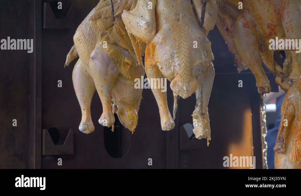 Hanging whole chickens smoking over fire or coals at summer local food ...