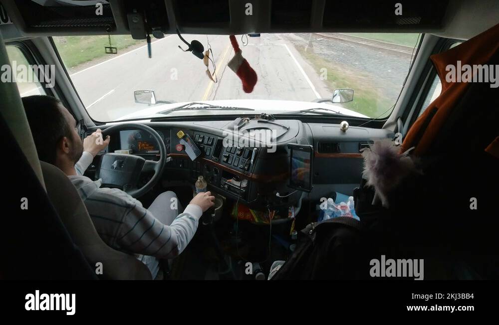 Inside the cab view of a semi truck. Middle aged man driving across ...