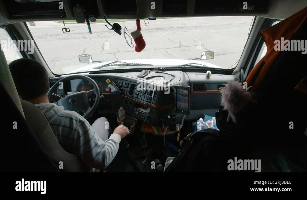 Inside the cab of a semi truck. A middle aged truck driver driving out ...