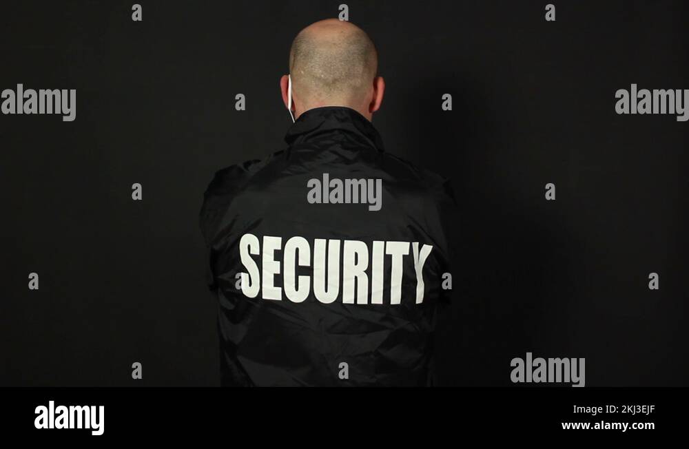 Bald Security Guard / Bouncer wearing black jacket turns with folded ...