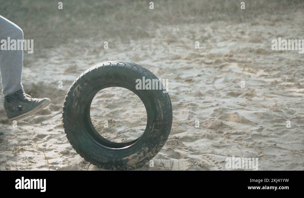 The boy hits the tire with his foot. the tire is rolling. Close up ...