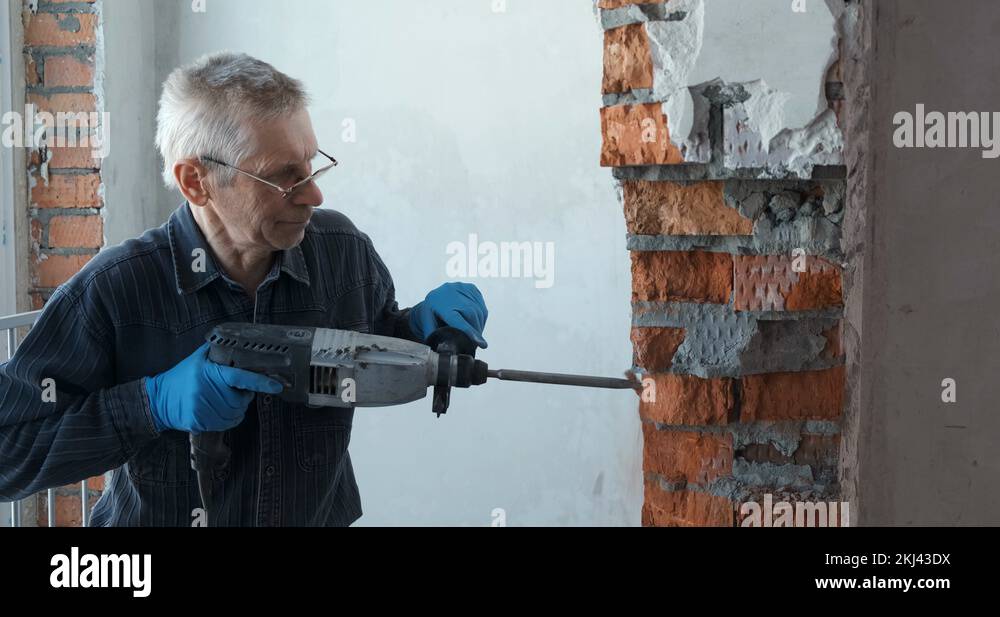 Man demolishes wall, perforator, brick crumbles, plaster flies off in ...