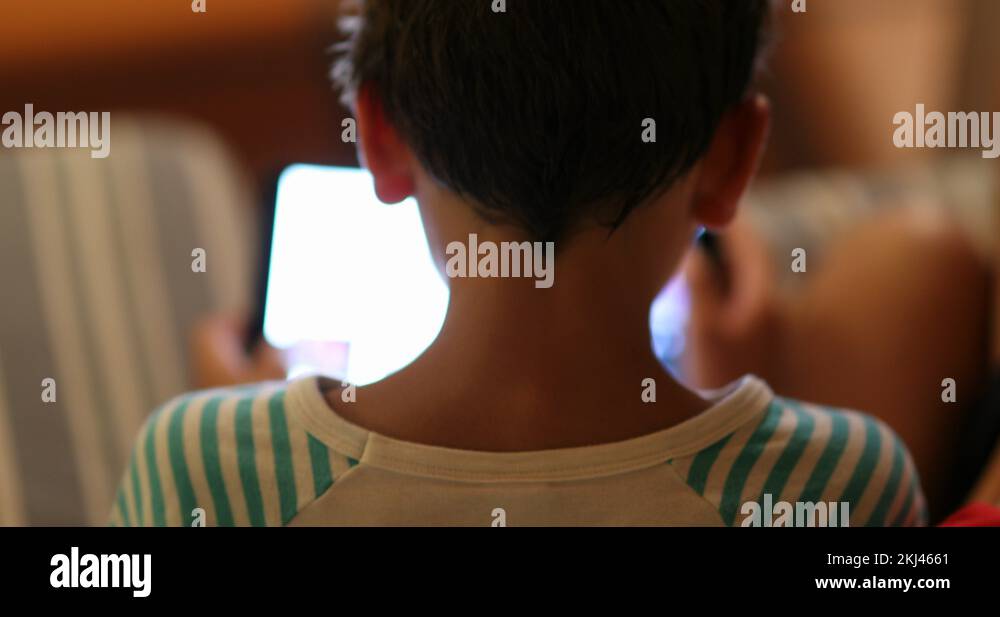 Boy staring at screen at night. back of Child watching content online ...