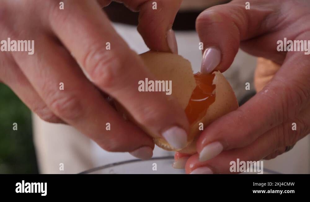 Women cracking open an egg while separating the egg white from the yolk Stock Video Footage - Alamy