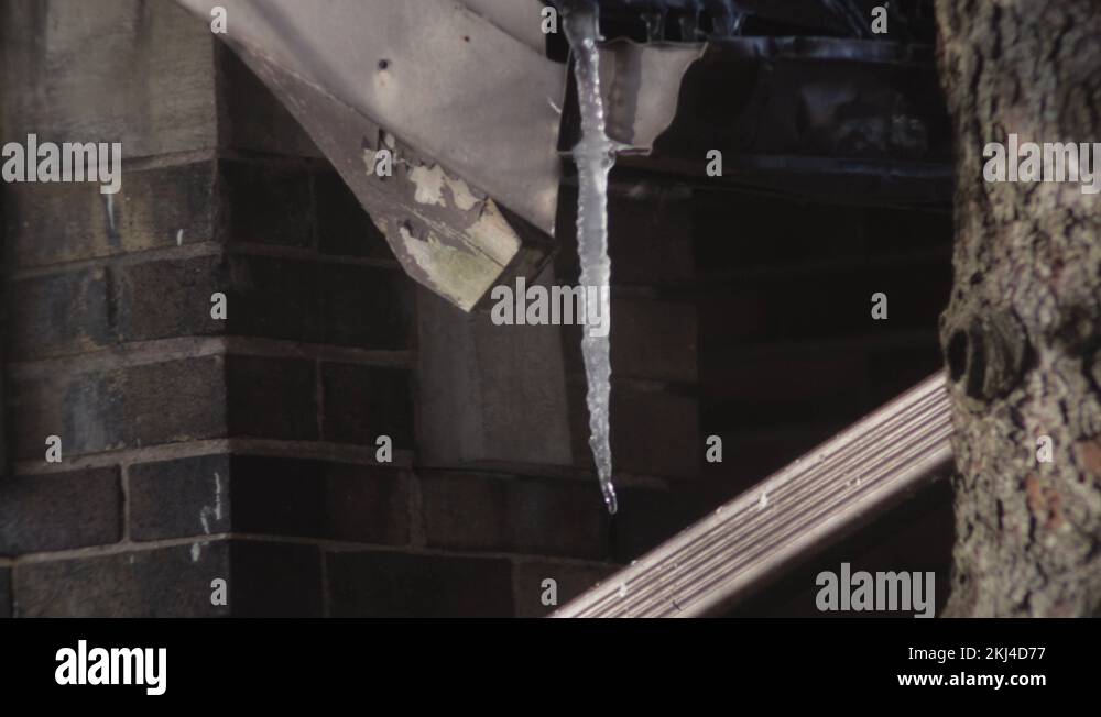 Long And Thick Icicle Hangs On The Drain Pipe In Roof.- panning shot ...