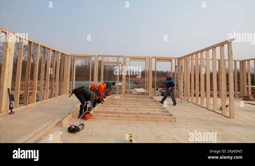 Builders lift and move the wall frame on place. Frame house under ...