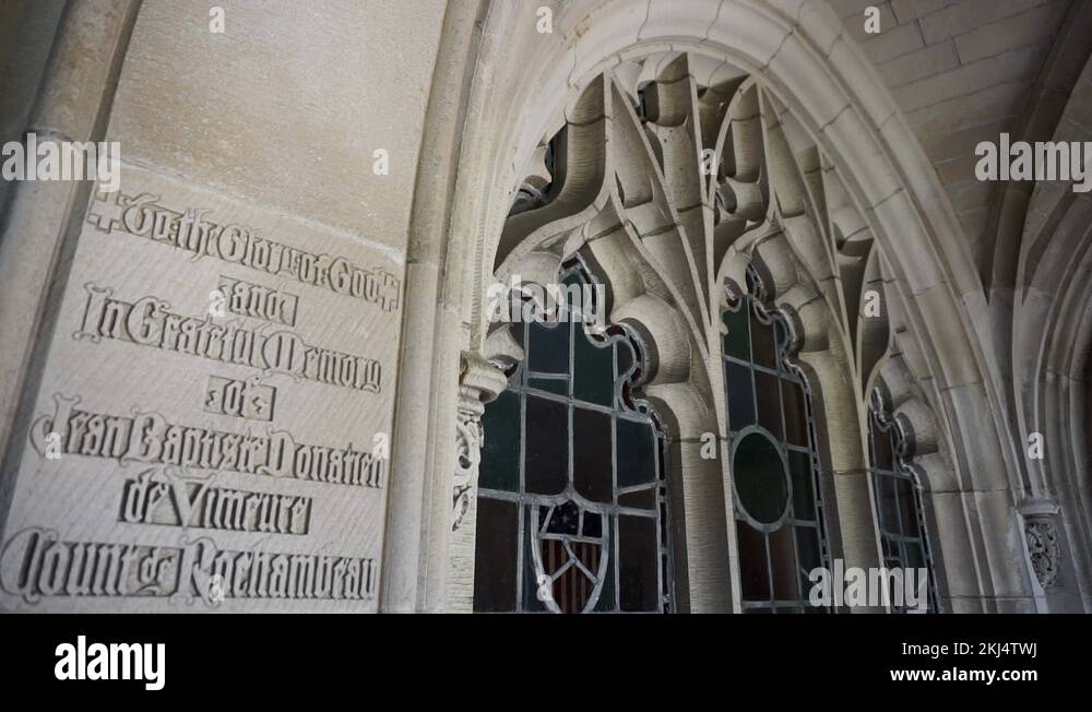 Camera tilts down on leaded glass window with tracery and gothic script ...