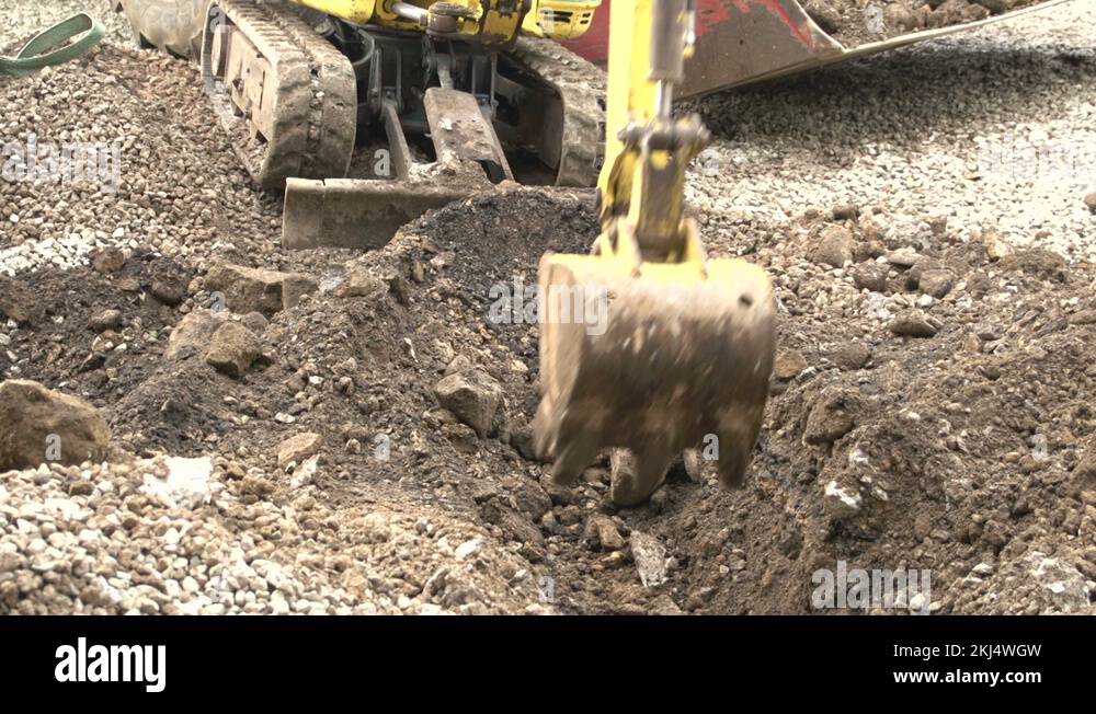 Mini Digger arm digging trench from some pipes. The machinery is ...