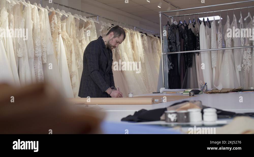 The tailor drawing a pattern on cloth on a desktop in dress atelier. 4K ...