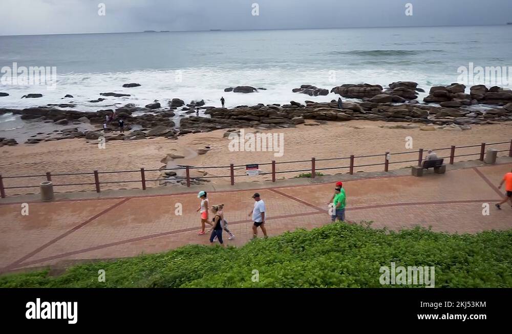 People walking on Umhlanga Rocks beach promenade with ocean and rocks ...