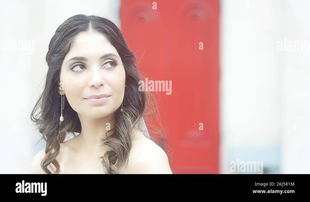 A pretty bride posing for her bridal photos in front of red church ...