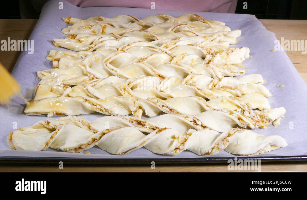 Woman coating puff pastry cheese twists / straws with beaten egg. (part ...