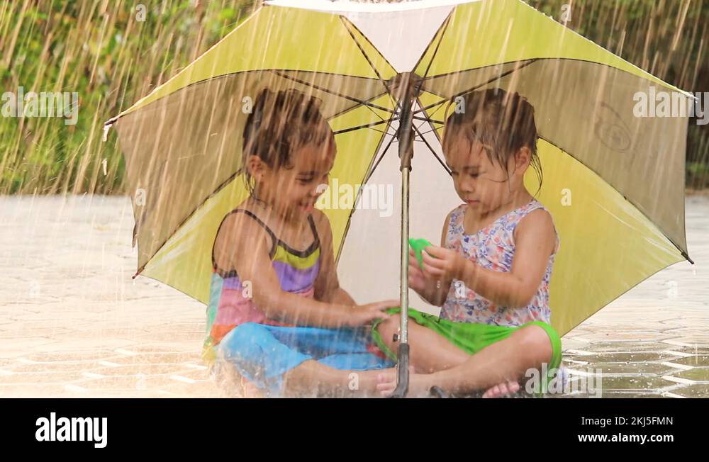 Cheerful siblings little girl having fun in rainy with umbrella at ...
