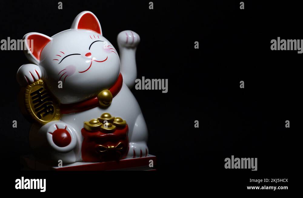 Closeup shoot of white and red shiny chinese lucky cat waving a paw ...
