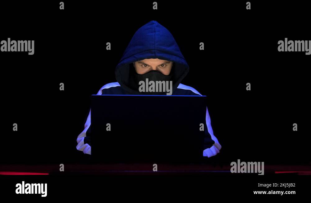 Hacker in hood and mask coding and programming using laptop. Cybercrime ...