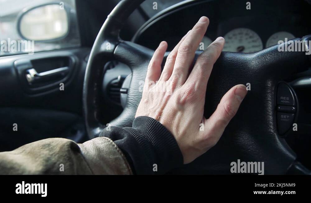 driver's hand on the steering wheel of a car while waiting for a ...