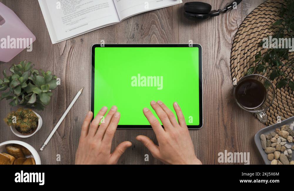 Horizontal orientation tab with green screen. Top view. Hands typing ...