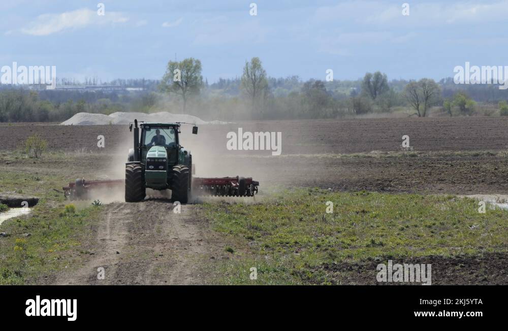 Farmer on Tractor Plowing Dusty Arid Soil. Farm Car Followed. Tractor ...