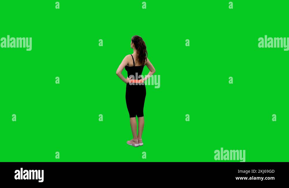 Slender girl in black bodysuit doing stretching exercises against green ...