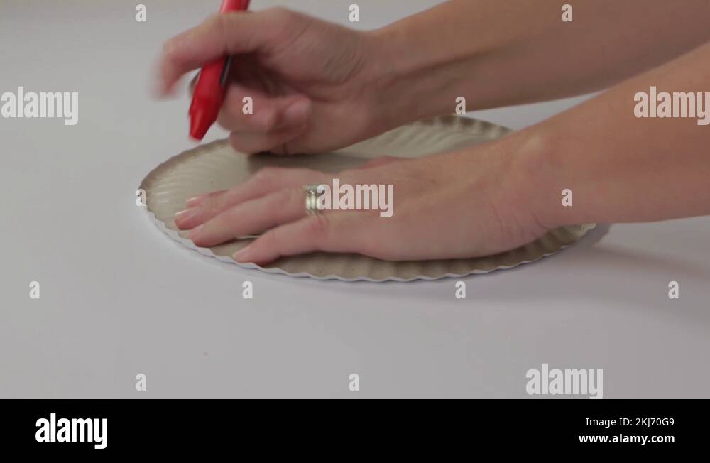 Woman drawing on a paper plate with a crayon for a creative activity ...