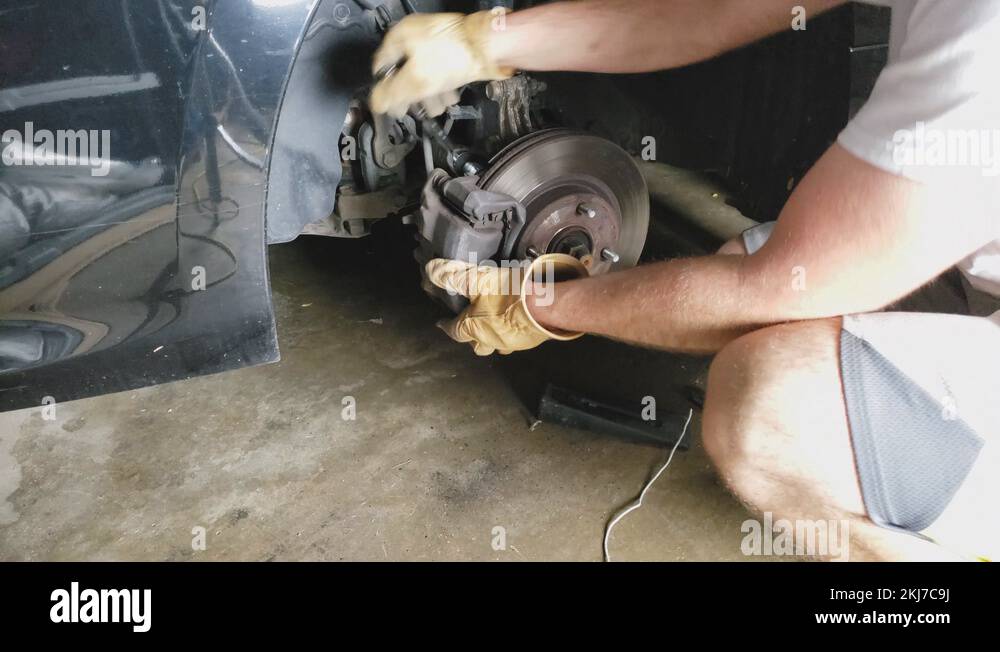 Loosening or unscrewing nuts from brake assembly in passenger car front ...