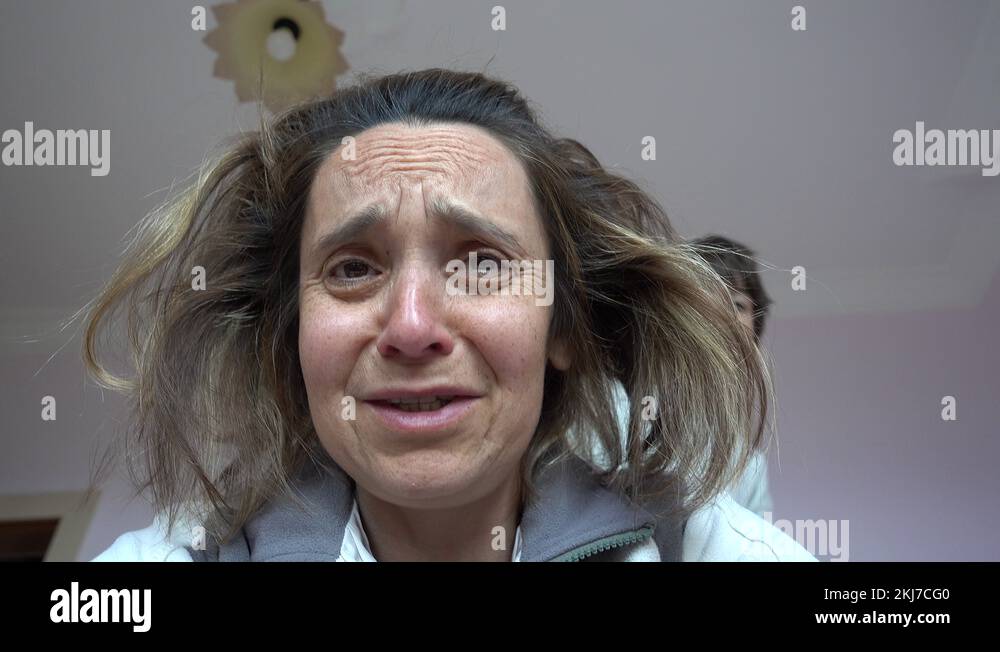 Weeping mother with disheveled hair and her son in the background Stock ...