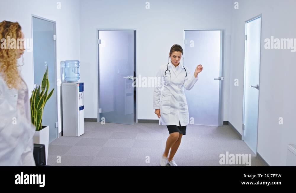 In a modern hospital corridor group of funny dancing doctors and nurses ...