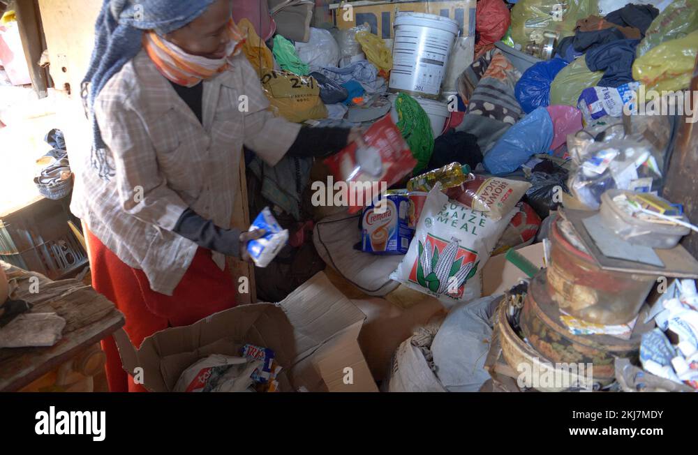 Black African woman unpacks a food parcel in squatter camp that was ...