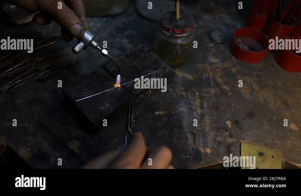 blacksmith heats a piece of wire with a gas blow torch in their ...