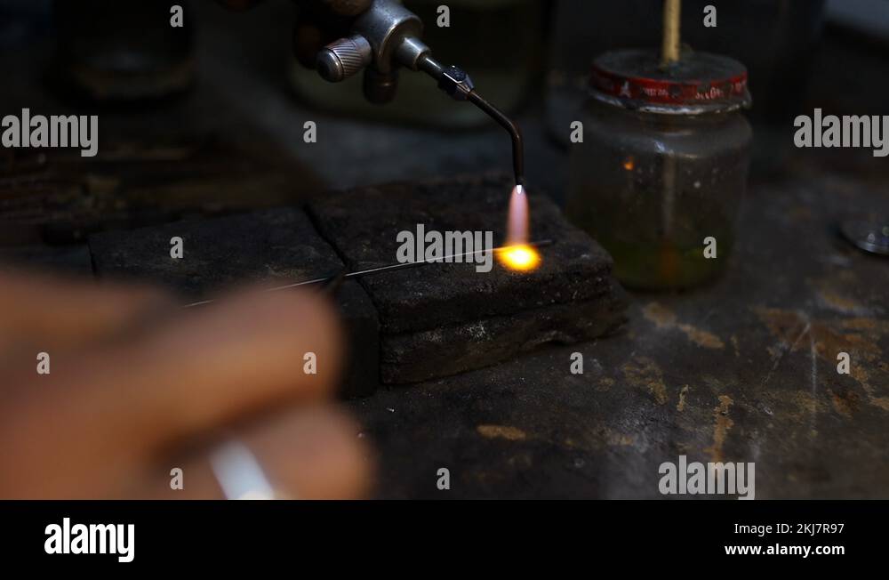 blacksmith heats a piece of wire with a gas blow torch in their ...