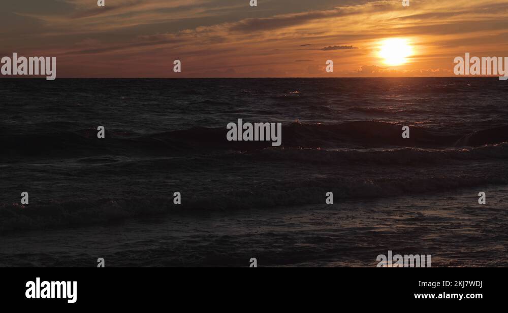 The sandy coast with a tidal wave at sunset, stones, sand, waves ...