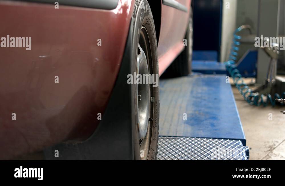 Car mechanic is removing the wheel cap and setting camber caster gauge ...