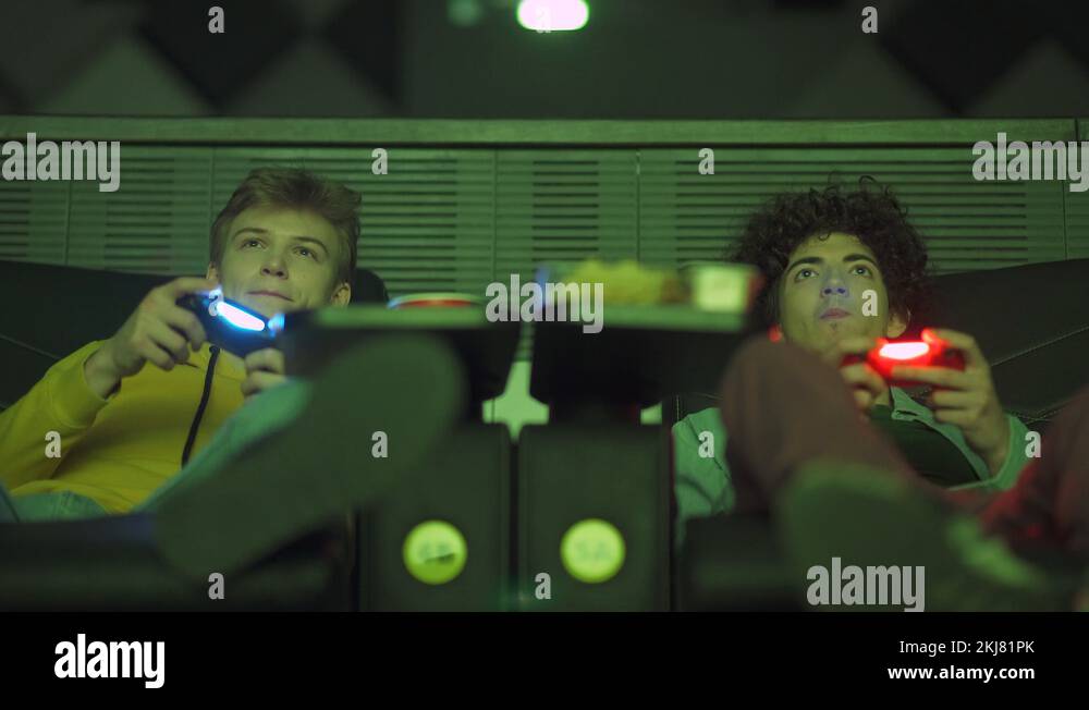 Gamers playing in a movie theater, two friends playing video games on a ...