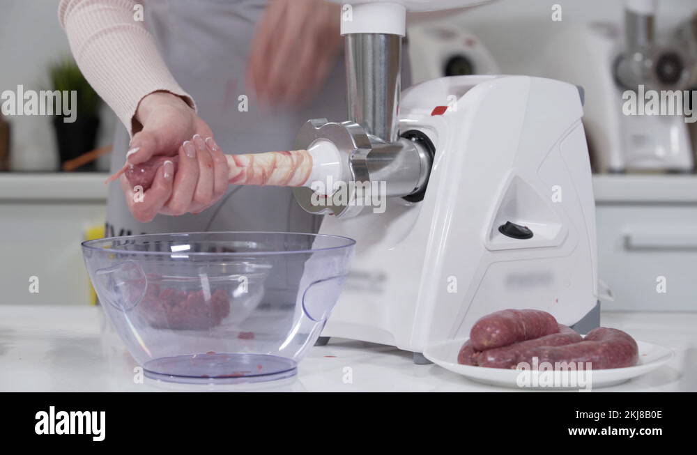 Woman in apron cooks sausages in traditional way using sausage filler ...