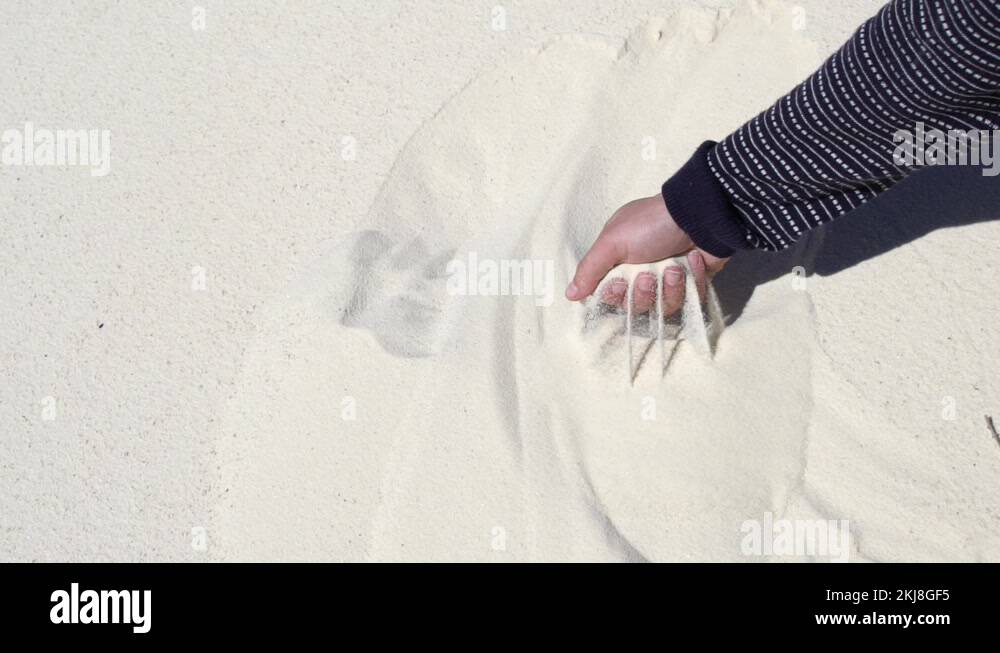 Female hand with rings on sifting through white sand really fine sand ...