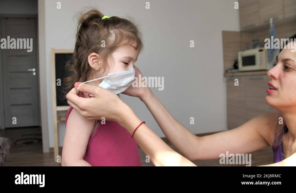 Mom tries on a medical mask for her little daughter. Stay home mom ...
