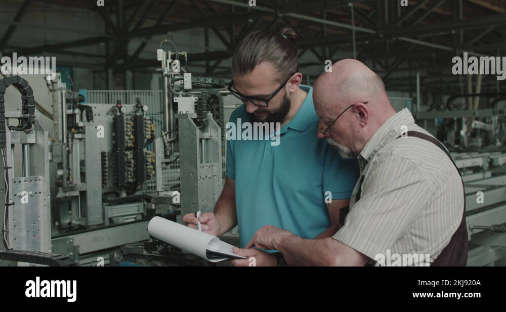 Two engineers of industry stand at facility, have discussion and use ...