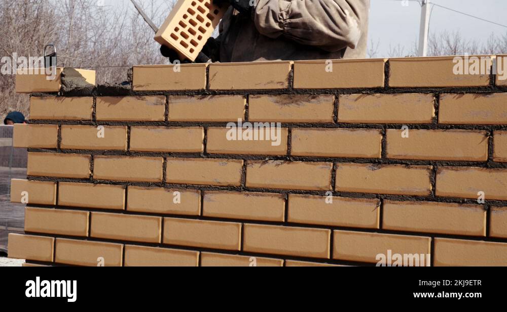 Builder bricklayer finishes row of brickwork, in frame is finished ...