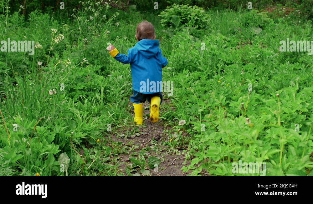 Funny active toddler baby boy running along a path and then turns to ...