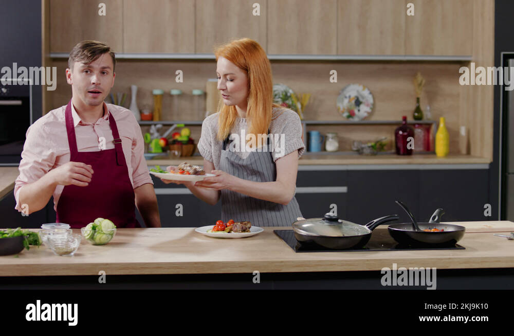 Cooking show hosts chefs, male and female, showing cooked dish into ...