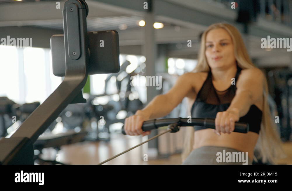 woman pulling weight on sports trainer in fitness club. fit girl doing ...