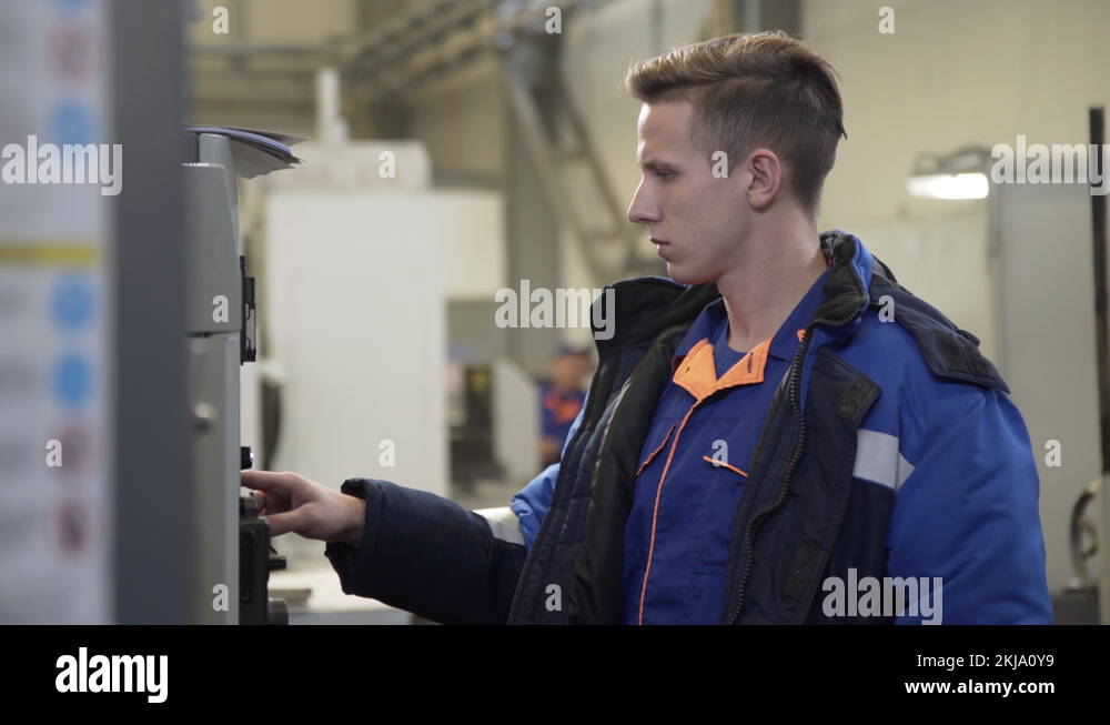 Young male operator of CNC milling machine stands at control panel in ...