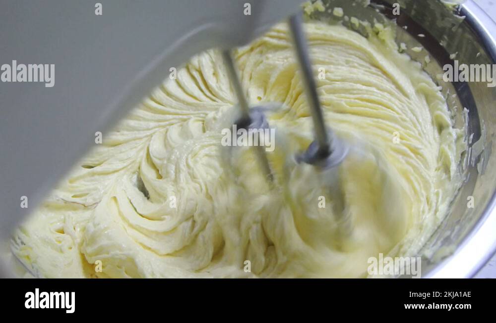 Butter, sugar and other ingredients are mixed together using a hand ...