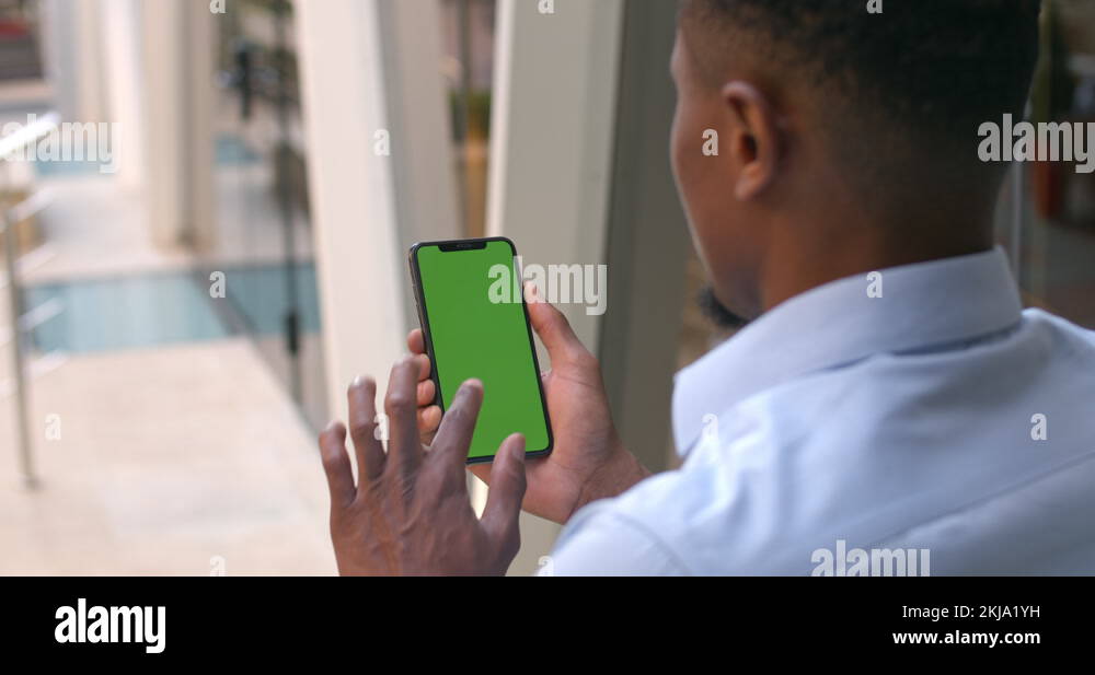 Guy hands using phone with mock up screen. Over shoulder view of afro ...