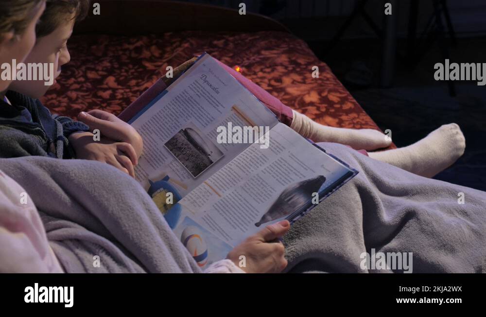Mother and son read bedtime stories. Covered with a plaid. Tells ... Mother and son read bedtime stories. Covered with a plaid. Tells ...