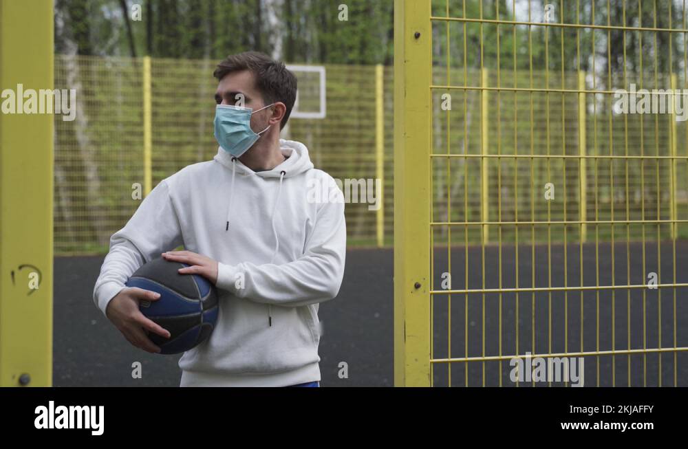 A male sportsman basketball player with a ball in a mask looks on the ...