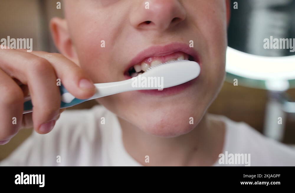 Funny handsome teen boy brushing his teeth using toothbrush, posing on ...