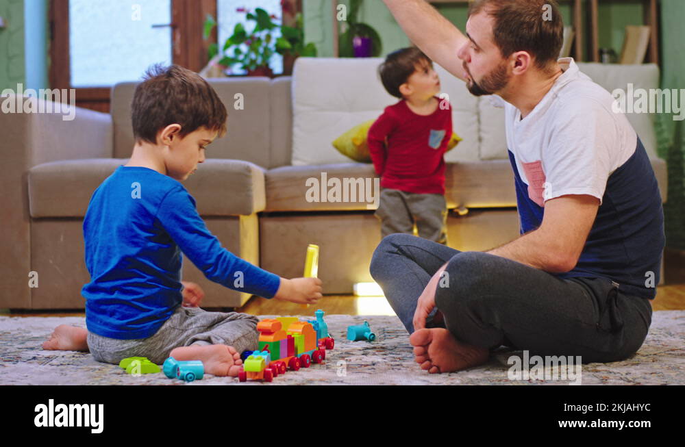 Attractive dad with his charismatic son playing together while sitting ...