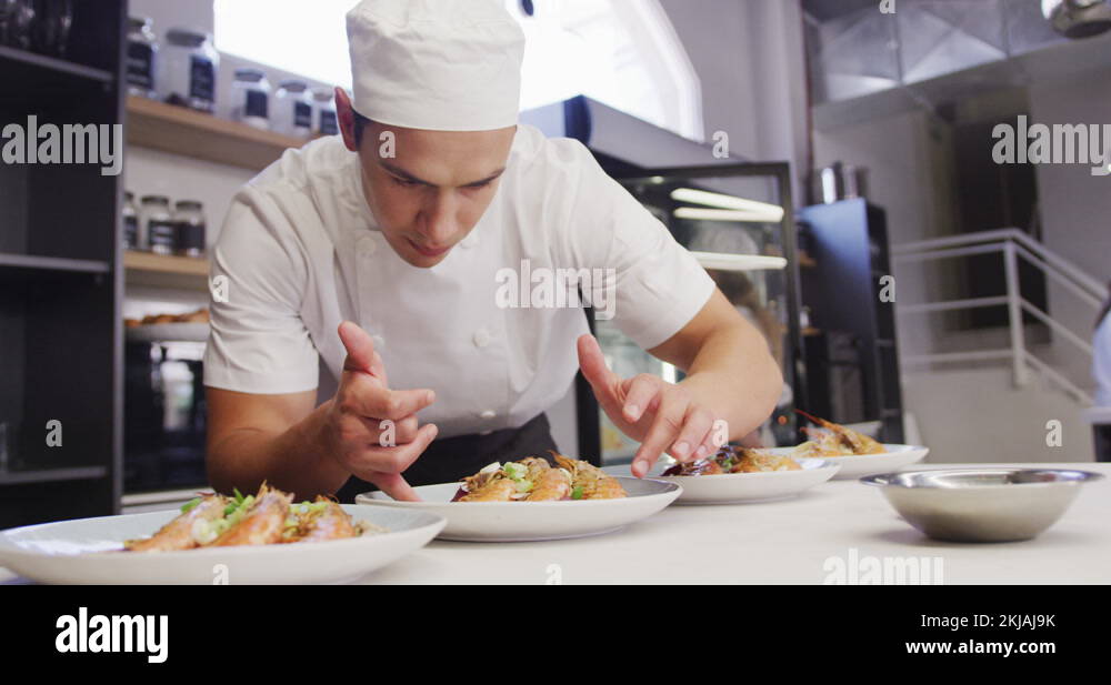Mixed race male chef wearing chefs whites in a restaurant kitchen ...